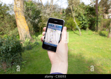 A hand holds a smartphone displaying a map application, with a field of ...
