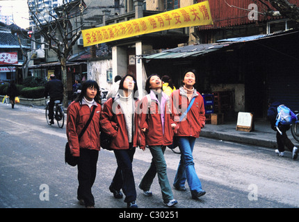 Four teenagers walking down a street with two of them hugging Stock ...