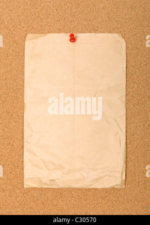 Wrinkled brown envelope attached to cork board. As backdrop or ...