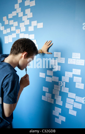 Teenage boy revising for Maths A Level with revision cards stuck on his ...