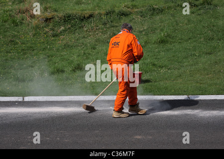A track marshal cleaning the track surface after an oil spillage, at ...