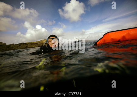 A diver on the surface waits to be picked up by the approaching dive ...