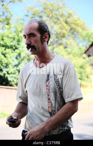 Outdoor portrait of Ukrainian senior man sitting in summer garden with ...