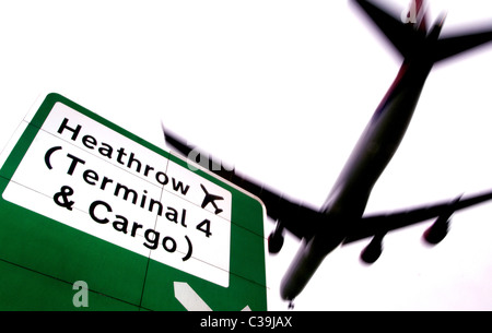 An aeroplane flying above road signs near Heathrow International ...