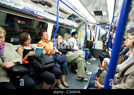 London Underground commuters, reading books, on a bury commuter route ...