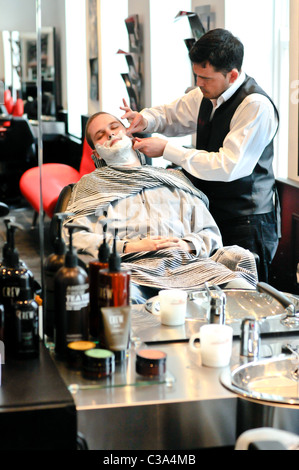 Young barber shaving with straight razor Stock Photo - Alamy
