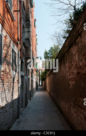 A a narrow alley between a building with red brick wall and another ...