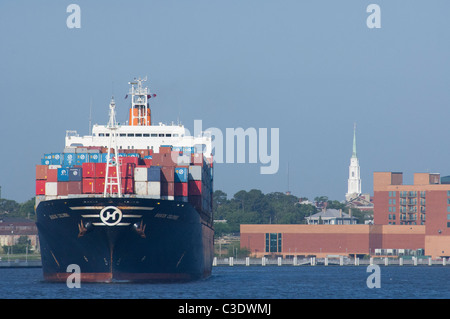 USA, Georgia, Savannah. Cargo ship entering the port, escorted by a tug ...