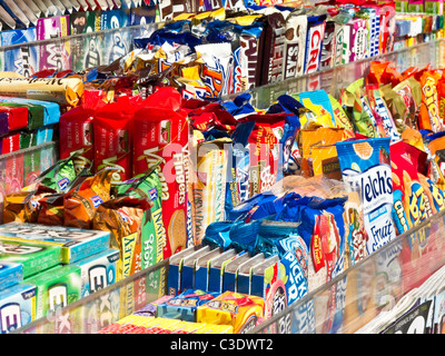 A street vendor selling candy and chocolate on the sidewalk at night ...
