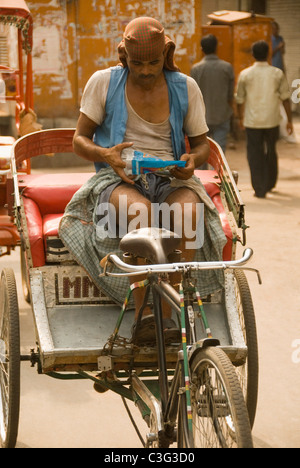 Indian rickshaw puller sitting on his rickshaw and waiting for ...