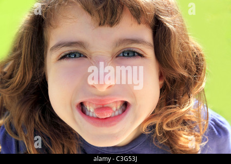A cute little curly toothless girl smiles and holds a red apple ...