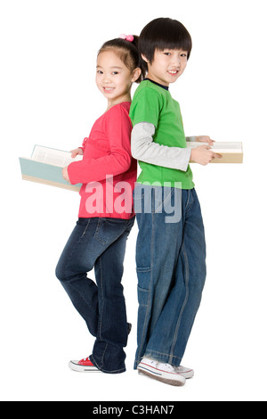 Studio portrait of a schoolboy reading a textbook while sitting on an ...