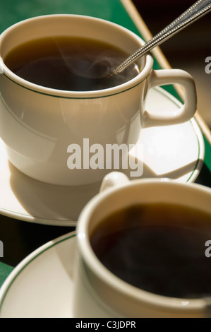 A vertical shot of a cup of hot coffee surrounded by coffee beans ...