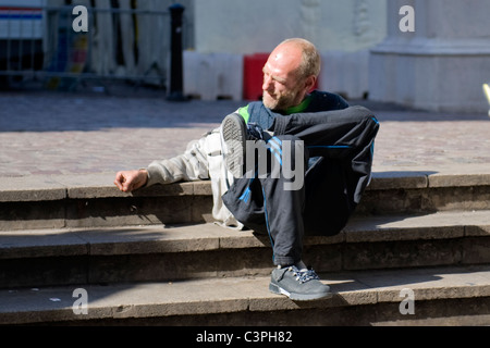 a homeless man sitting on some steps next to tower bridge in central ...