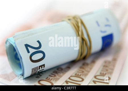 rolled up 20 euro notes in an elastic band on out of focus 10 euro ...
