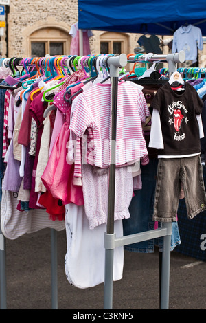 clothing stall with clothes hanging on racks selling both new and used ...