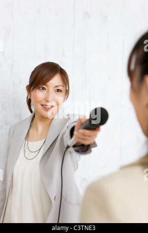 side view of journalist interviewing with microphone on white ...