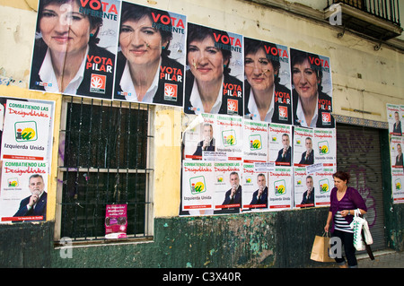 A woman walks past a campaign poster displayed outside the headquarters ...