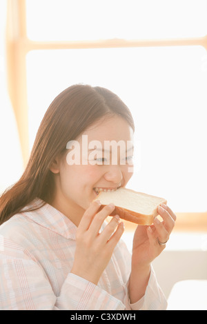 Young woman in pajamas eating tasty cereal rings on blue background ...