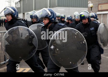 Police with short shields run round a corner during riot training Stock ...
