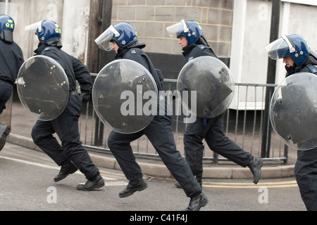 Police with short shields run round a corner during riot training Stock ...
