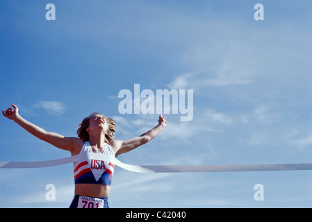 Female runner victorious at the finish line in a track race Stock Photo ...