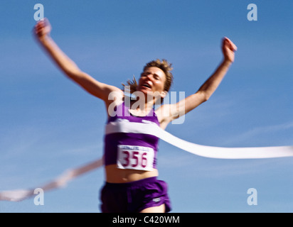 Female runner victorious at the finish line in a track race Stock Photo ...