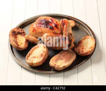 Appetizing roasted potatoes served in white ceramic bowl. Garnished ...