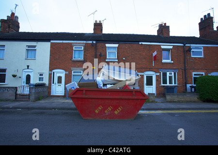Overloaded skip in English street at night Stock Photo - Alamy