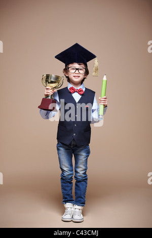 boy pick up the trophy wearing graduation cap Stock Photo - Alamy