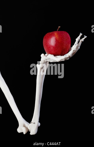 A skeleton arm and hand holding a red apple Stock Photo - Alamy