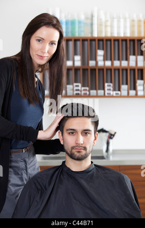 Styling female hair. Male hairdresser makes hairstyle for a young woman ...