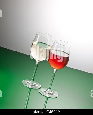 two glasses of red and white wine with grape, bottles at background ...