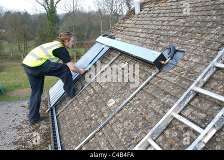 Engineers installing solar thermal evacuated tube array on the roof of ...