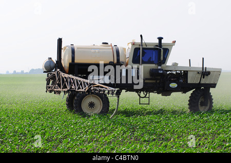 A self propelled crop sprayer treating a corn field with insecticide or ...