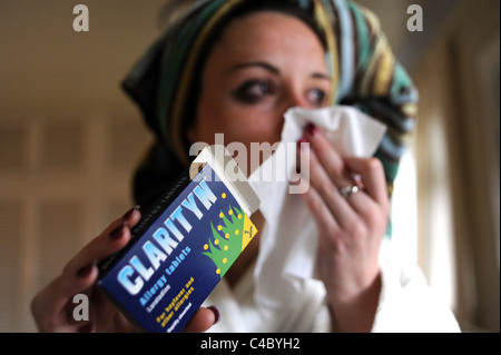 Allergic young woman with tissue and eye drops in park on spring day ...