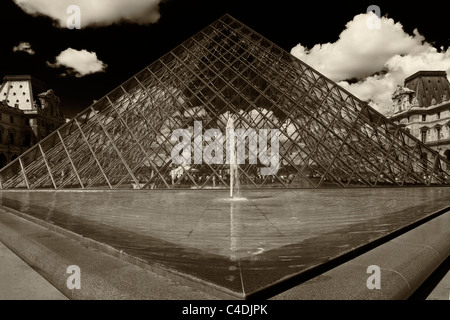 Low angle greyscale of the Louvre Museum under a cloudy sky in Paris in ...