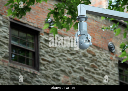 A small CCTV security camera mounted on a fence post in a rural area ...