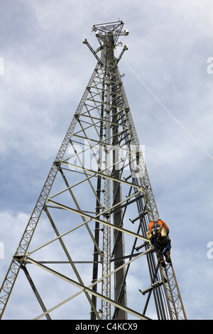 Telecom tower climber working on top of radio tower installing a ...