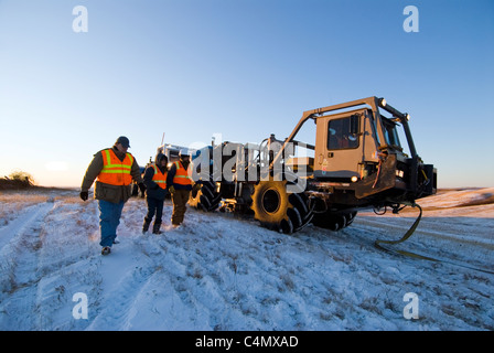 Workers around seismic vibrator trucks that are used for oil & natural ...