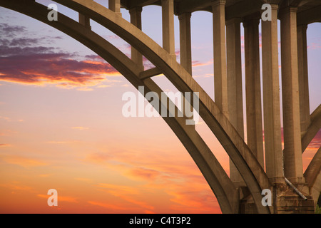 Highway bridge arch and structural supports against a river Stock Photo ...