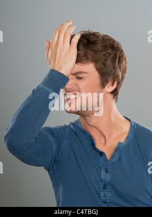 Irritated man with hand on forehead leaning against a wall Stock Photo ...