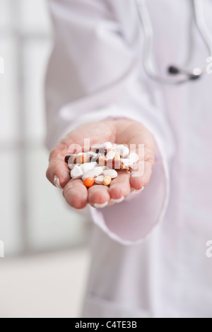 Cropped view of blurred doctor holding pills and glass of water near ...