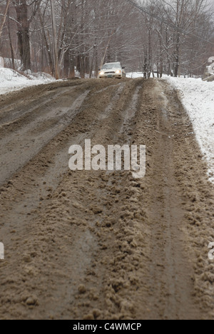 A car makes it’s way along a muddy road during mud season in Vermont in ...