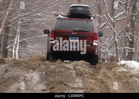 A car makes it’s way along a muddy road during mud season in Vermont in ...