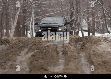 A car makes it’s way along a muddy road during mud season in Vermont in ...