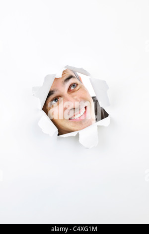 Man peeking through torn white surface Stock Photo - Alamy