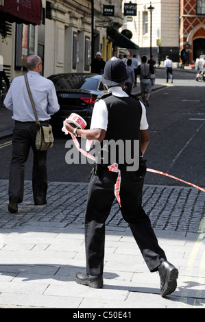 Metropolitan police officer rolling out tape to cordon off pedestrian ...