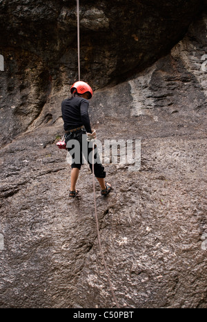A girl abseiling down a climbing wall. The origin of the abseil is ...