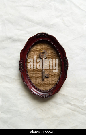 vintage key inside an oval shaped ornate frame on blue silk Stock Photo ...